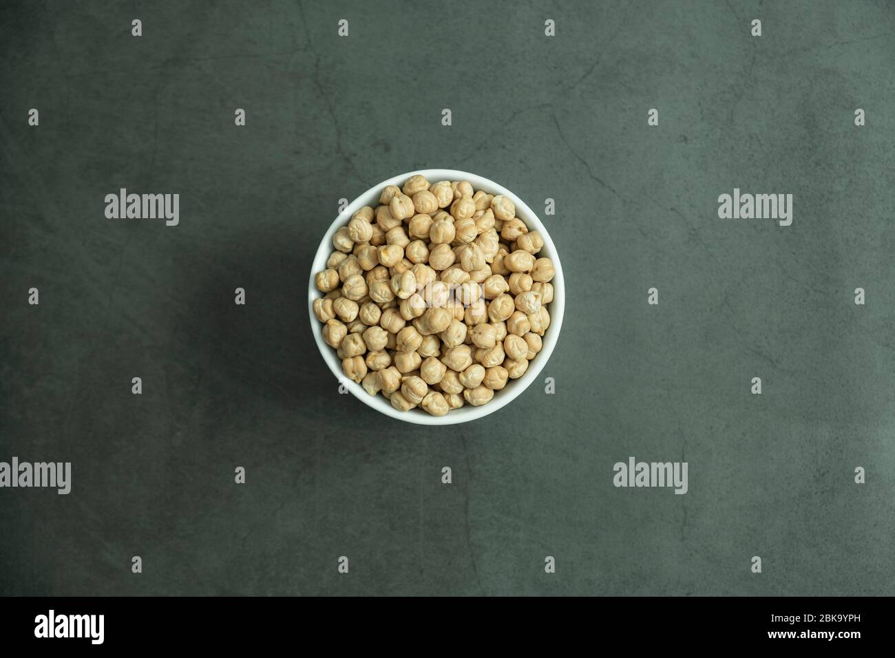 Chickpea in white porcelain bowl on stone, concrete background. Raw ...