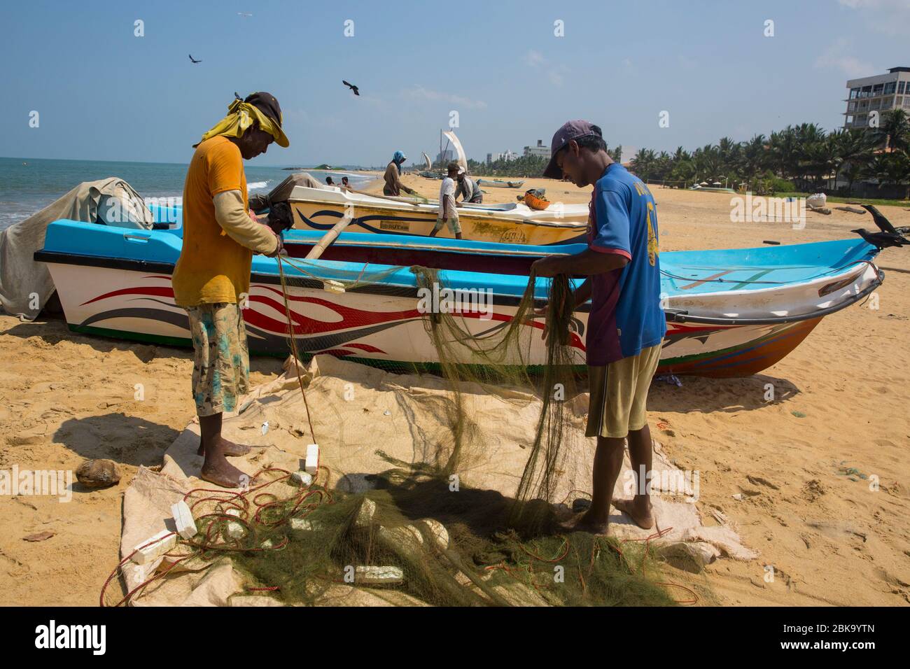 Fishermen repair fishing nets on the sea beach at Negombo, Sri Lanka ...