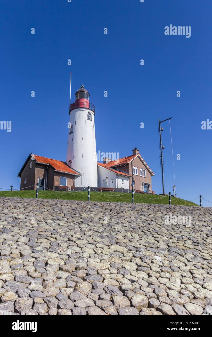 White lighthouse and houses on the top of the dike in Urk, Netherlands ...