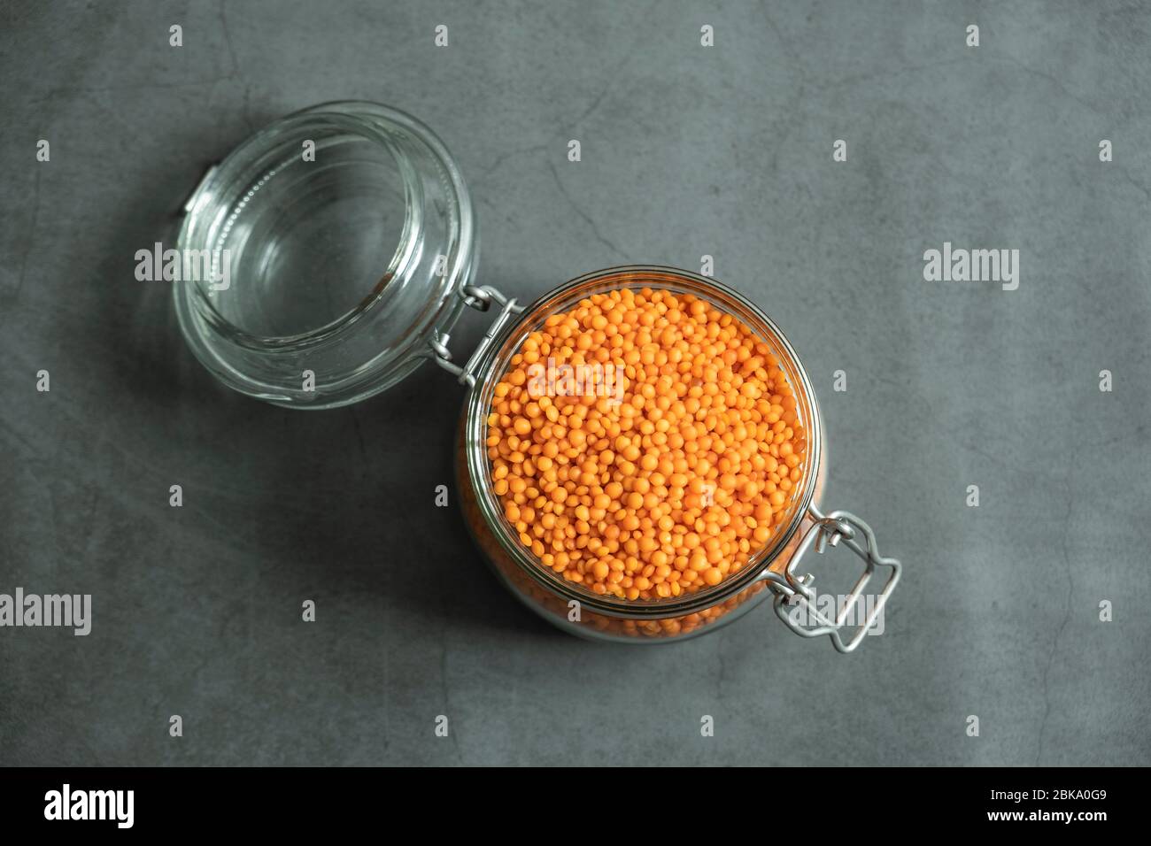 Red lentil in glass jar on stone, concrete background. Healthy, organic ...