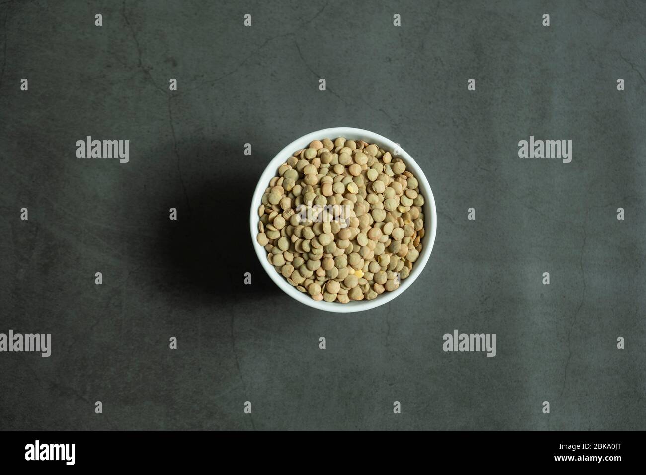 Green raw lentil in white porcelain, ceramic bowl on concrete, stone ...
