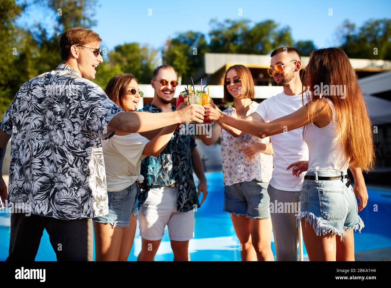 Group of friends having fun at poolside summer party, clinking glasses ...