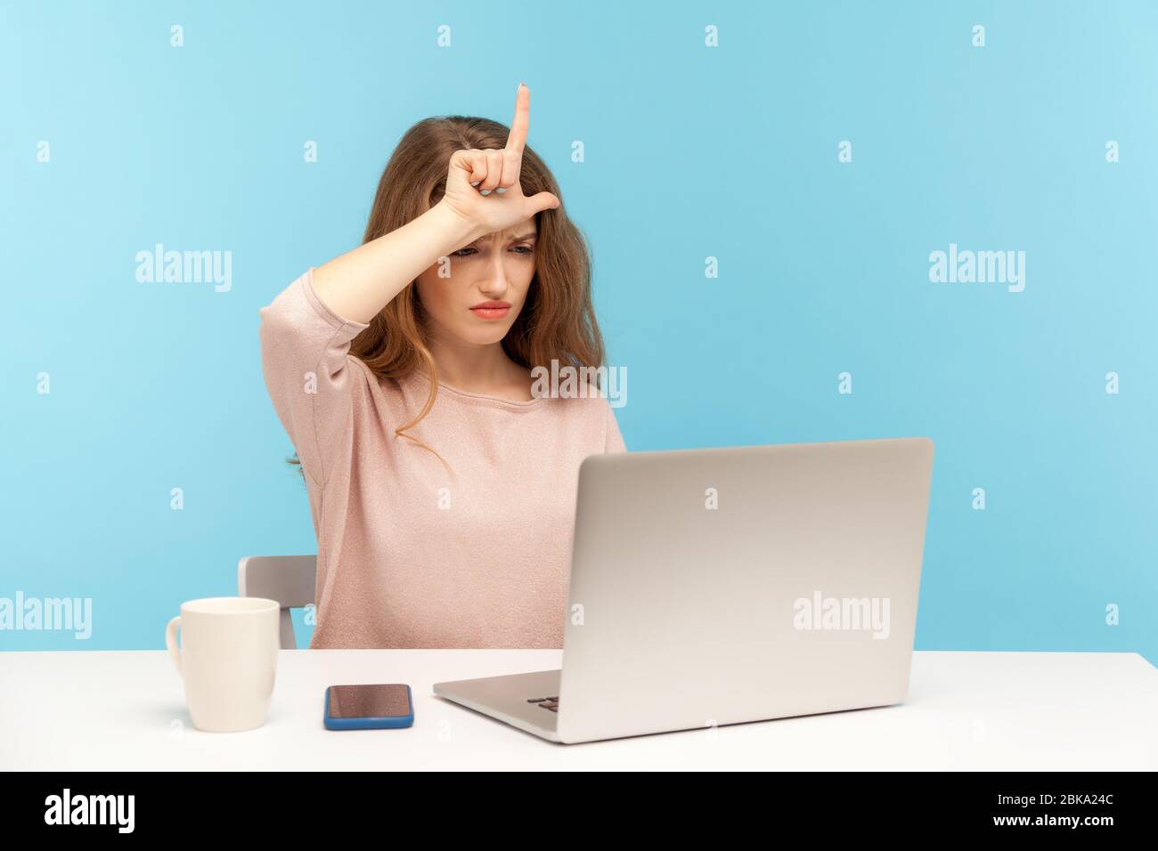 Lost job. Sad depressed young woman showing loser gesture to laptop ...