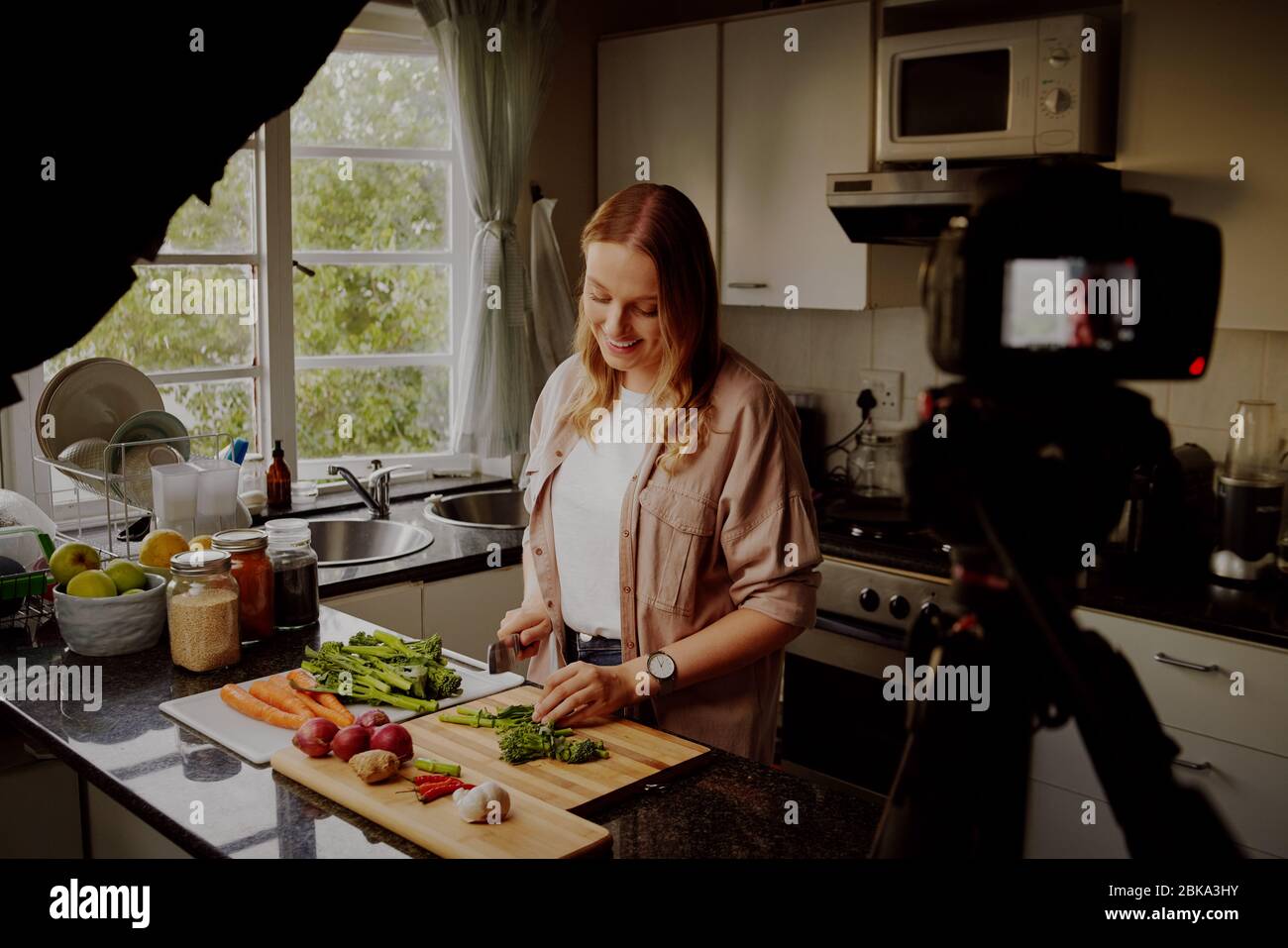 Woman in modern kitchen chopping fresh green vegetables to record food ...