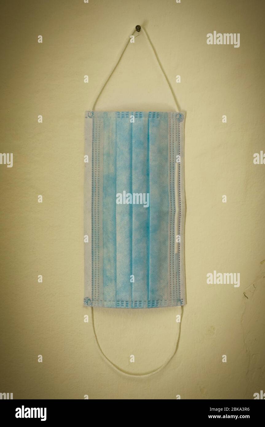 Surgical mask hanging from a nail on a yellow wall Stock Photo - Alamy