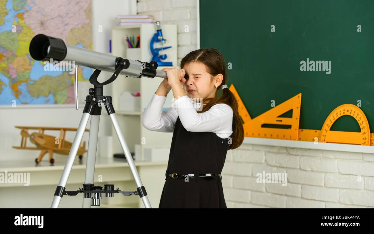 School girl looking through telescope. Little girl using telescope ...