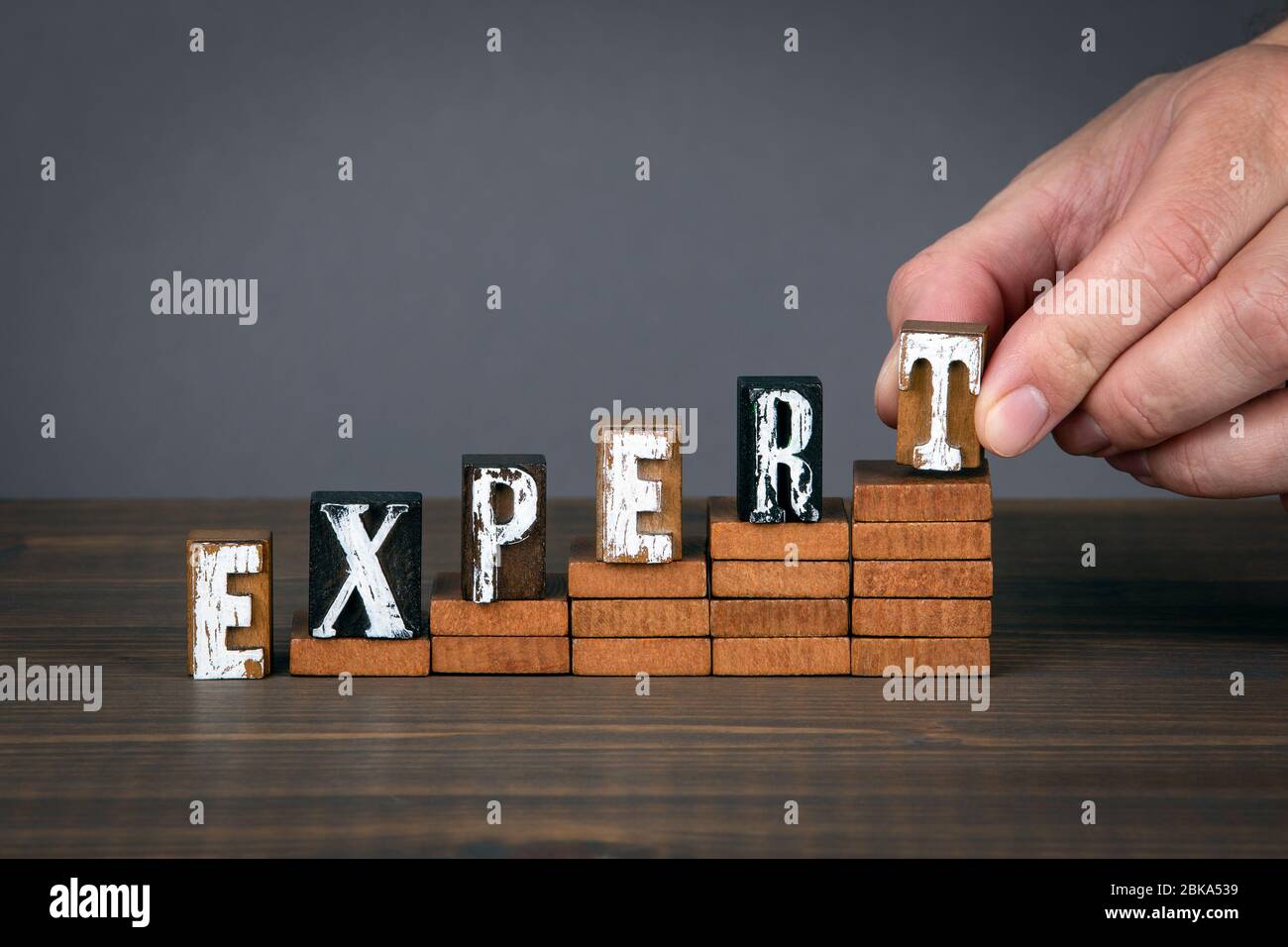 EXPERT concept. Wooden alphabet letters on steps. Gray background Stock ...