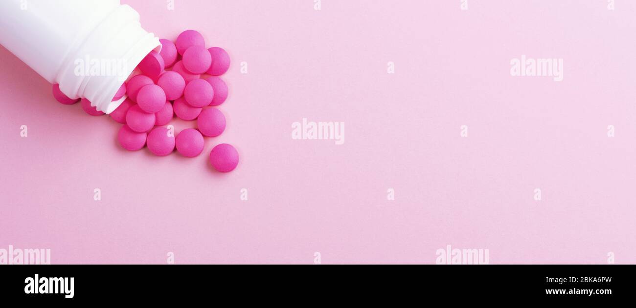 Pills of bright pink color are scattered from a white medical jar ...