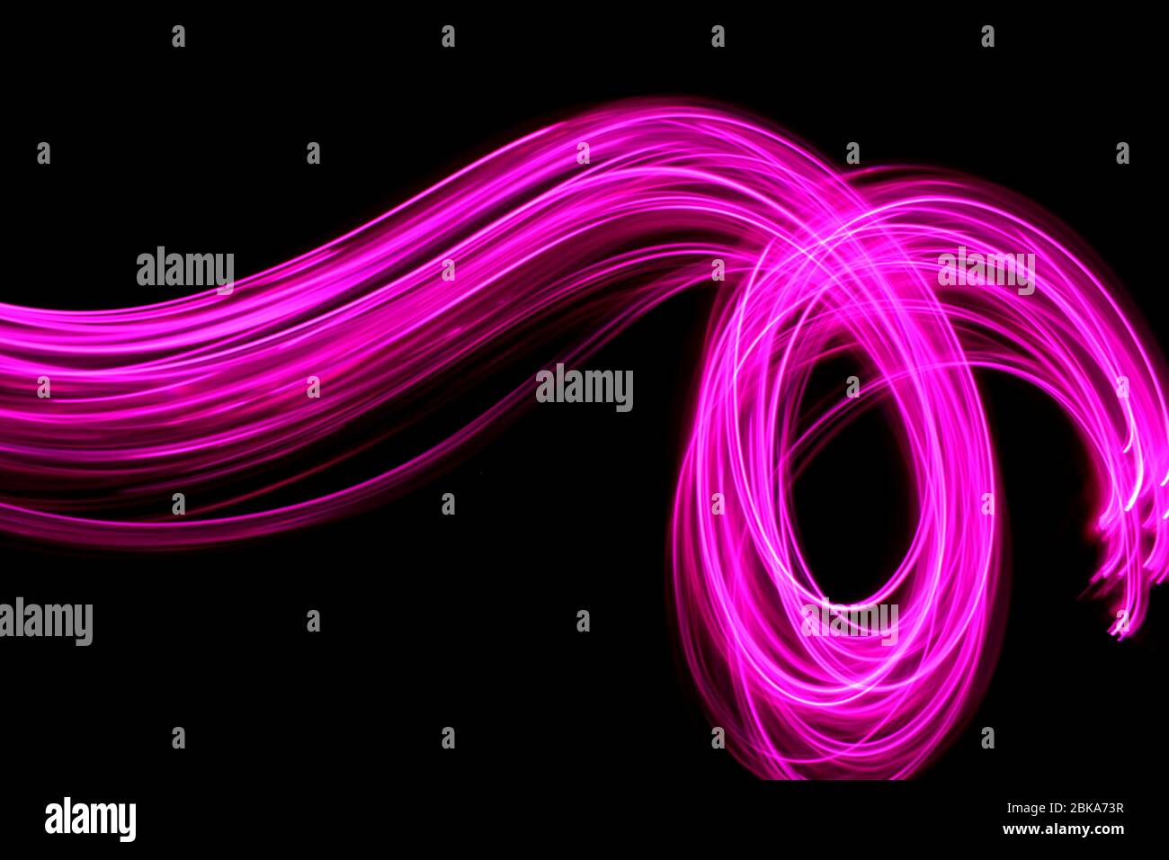 Long exposure photograph of neon pink colour in an abstract swirl ...
