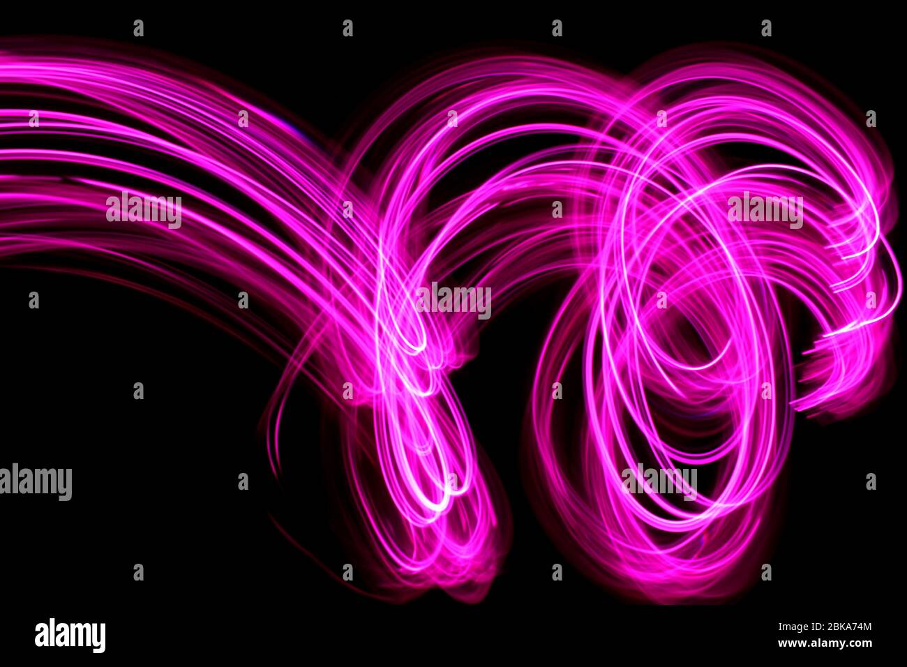 Long exposure photograph of neon pink colour in an abstract swirl ...