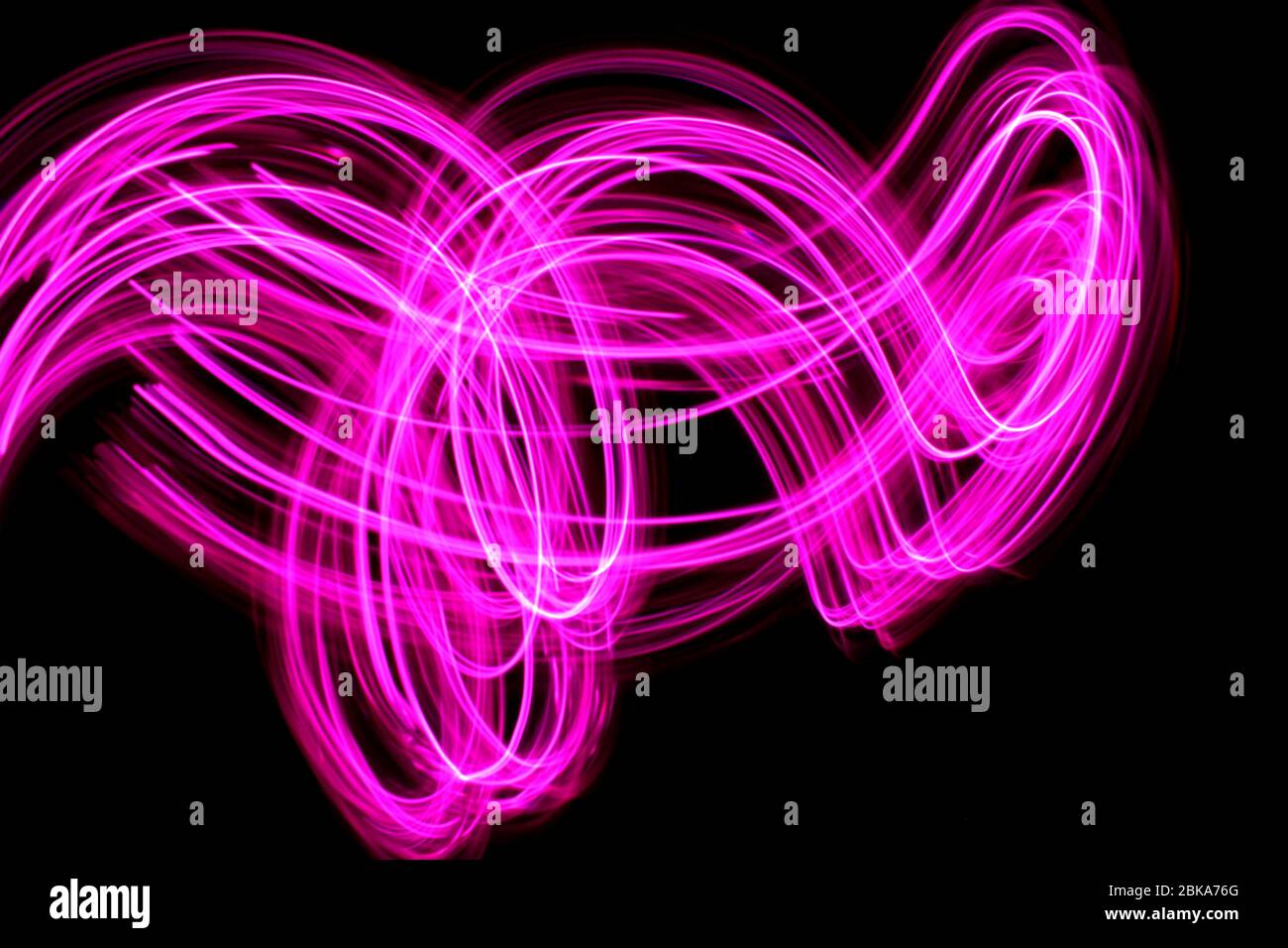 Long exposure photograph of neon pink colour in an abstract swirl ...