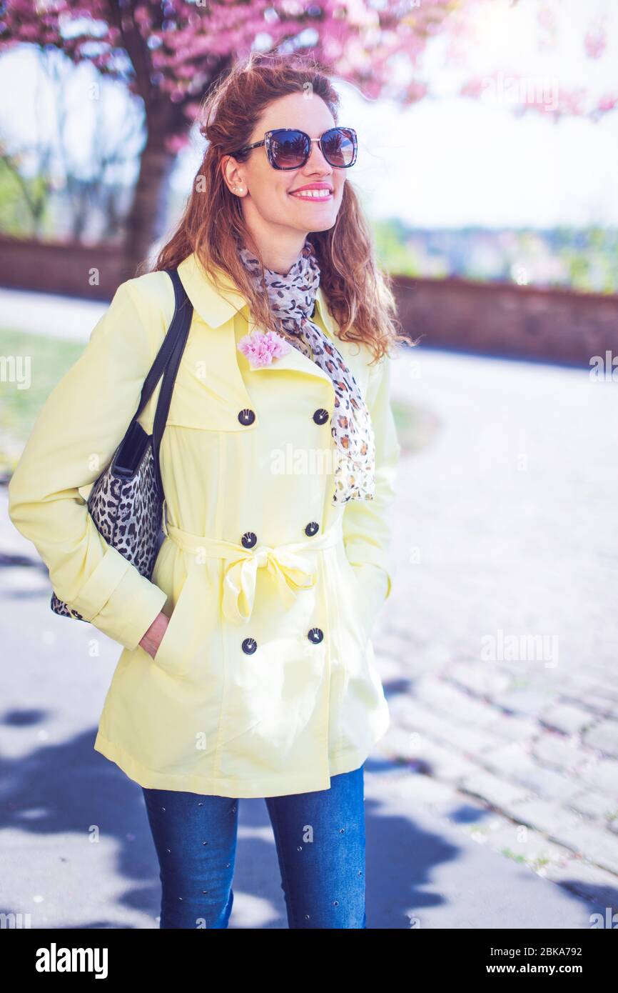 Happy young redhead woman walking in park during Sakura at springtime ...