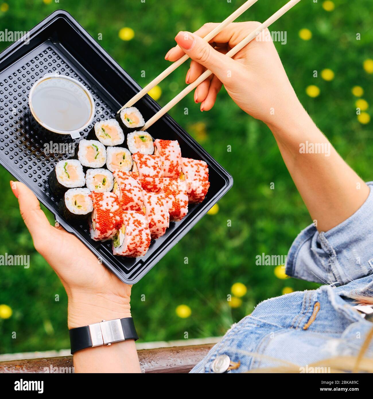 Hand holding sushi roll using chopsticks Stock Photo - Alamy
