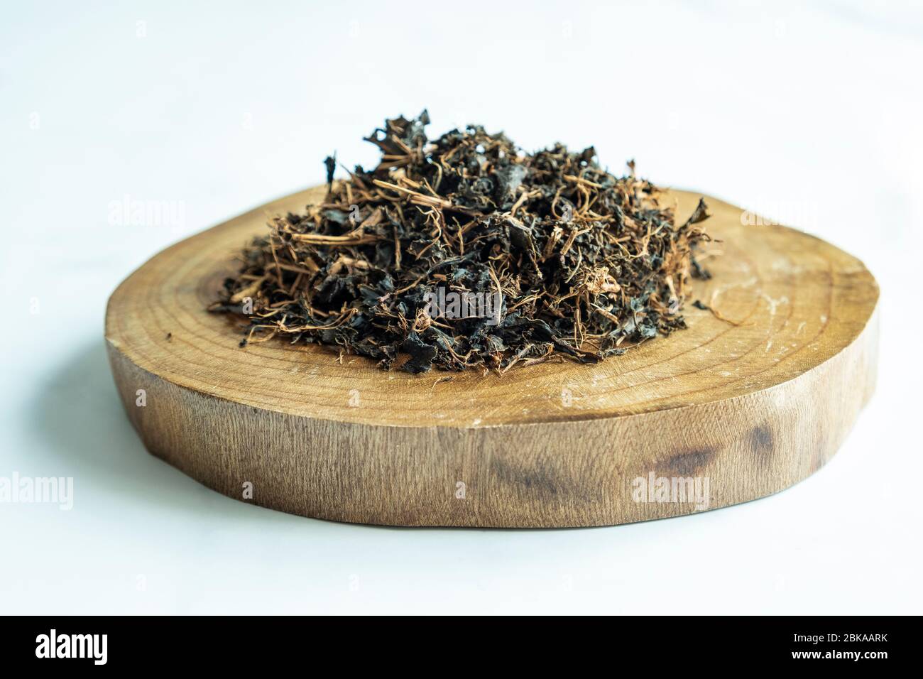 Dry black tea leaf in wooden platter on white background. Traditional ...
