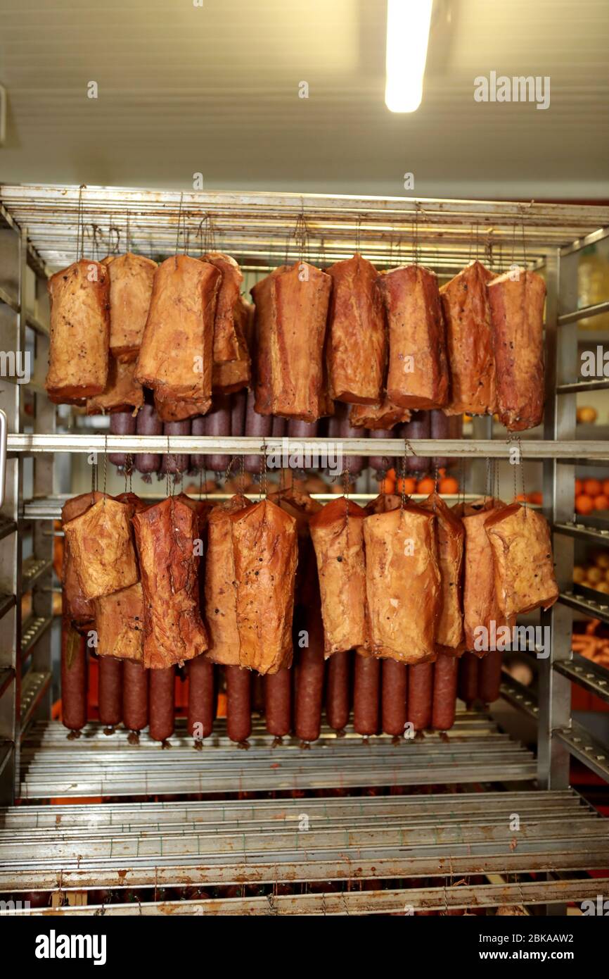 A worker at the meat processing factory, prepares sausages at the work ...