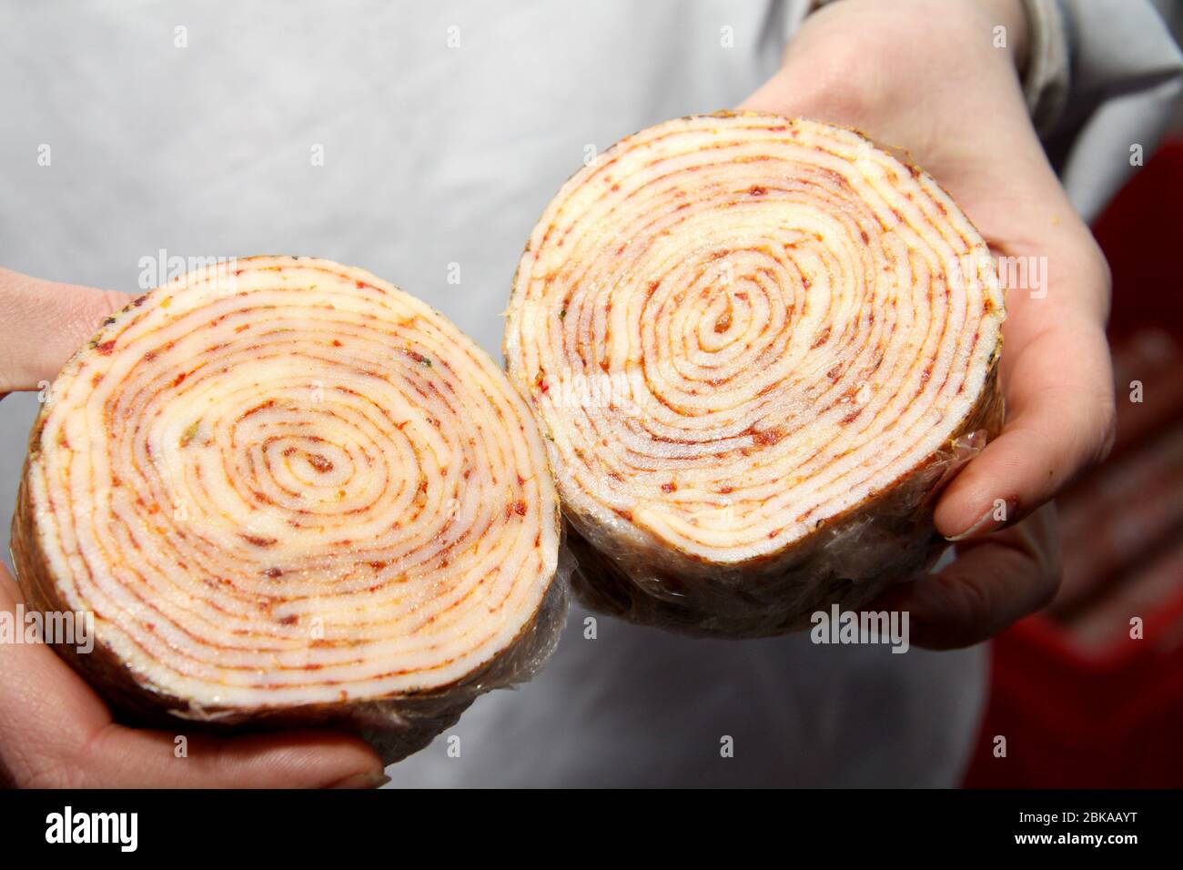 A worker at the meat processing factory, prepares sausages at the work ...