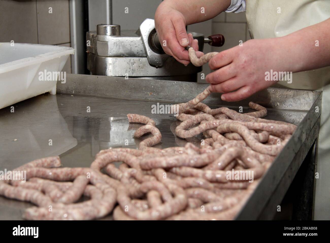 A worker at the meat processing factory, prepares sausages at the work ...