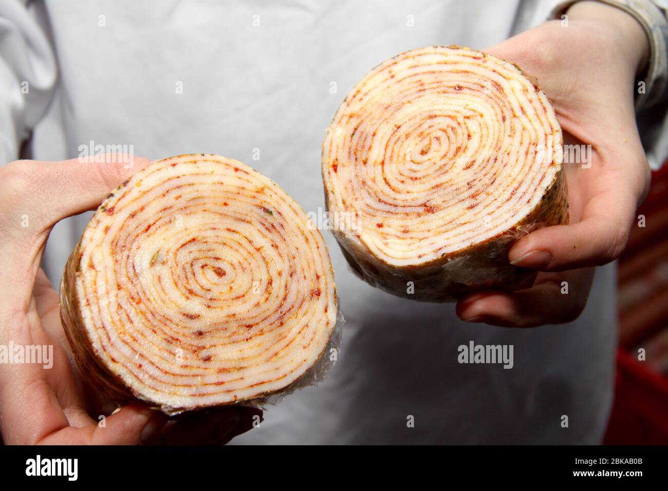 A worker at the meat processing factory, prepares sausages at the work ...