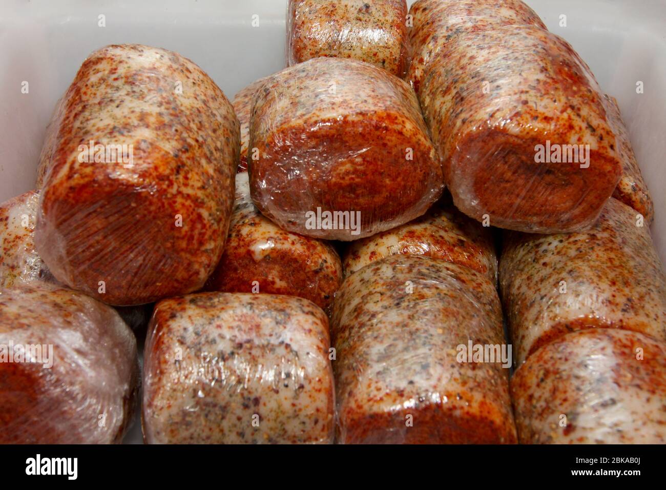 A worker at the meat processing factory, prepares sausages at the work ...