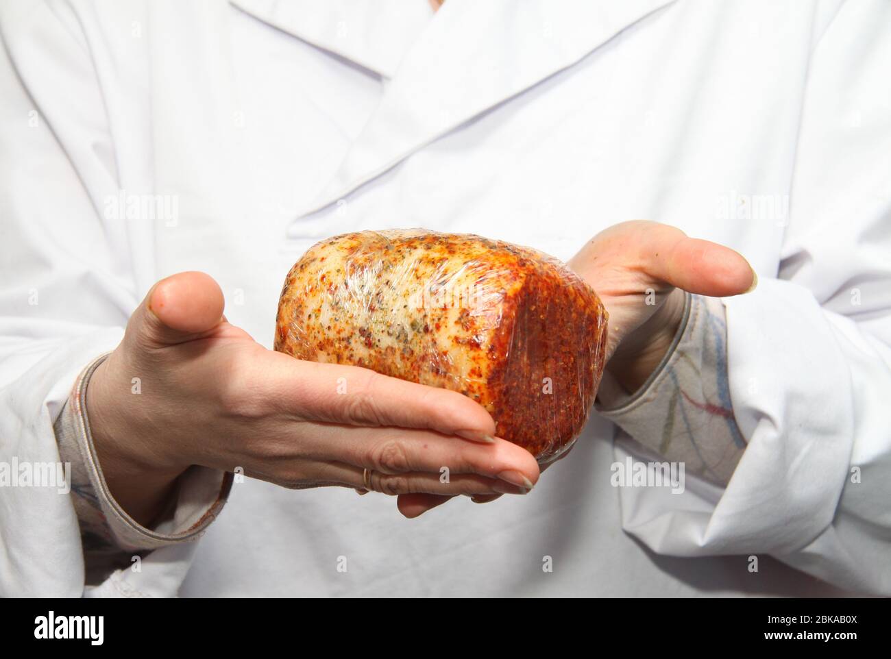 A worker at the meat processing factory, prepares sausages at the work ...