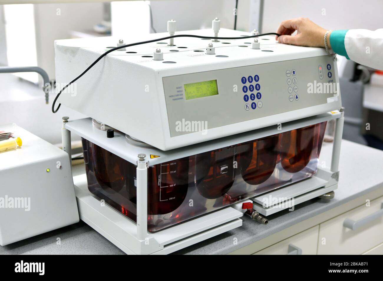 A female chemist conducts solubility tests of tablets and other dosage ...