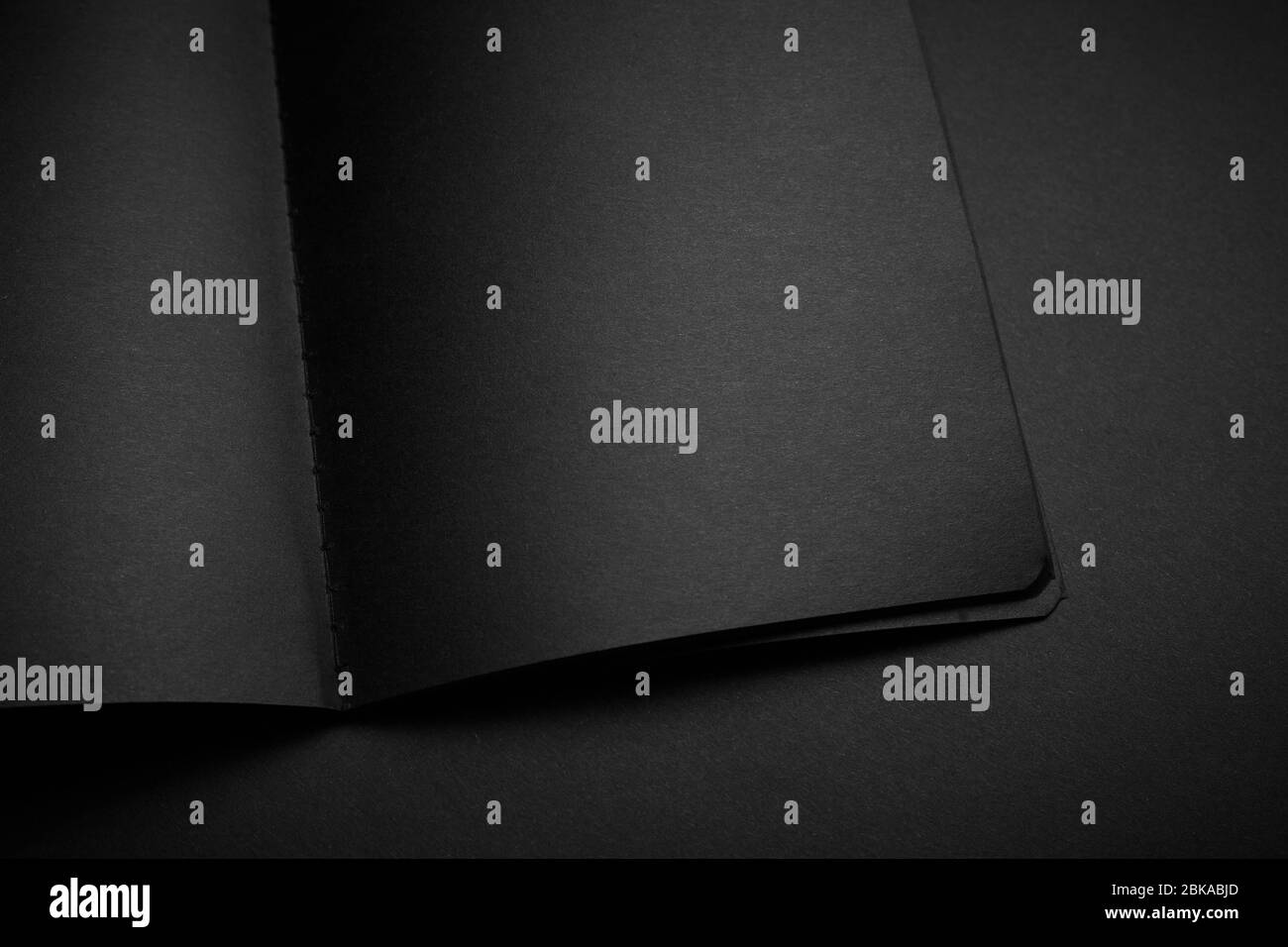 Blank black notebook on a black table, mockup photo. Blank black cover ...