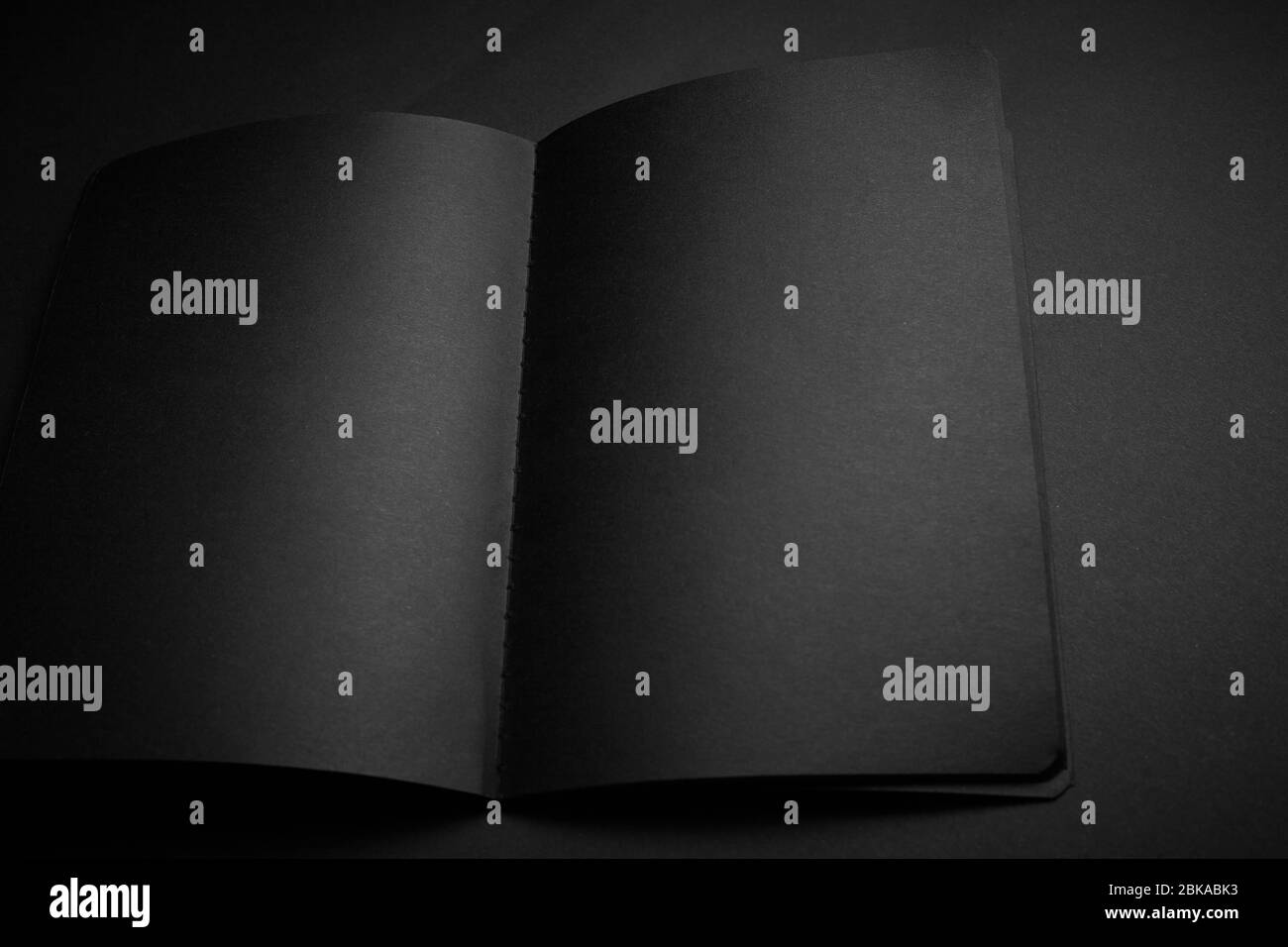 Blank black notebook on a black table, mockup photo. Blank black cover ...