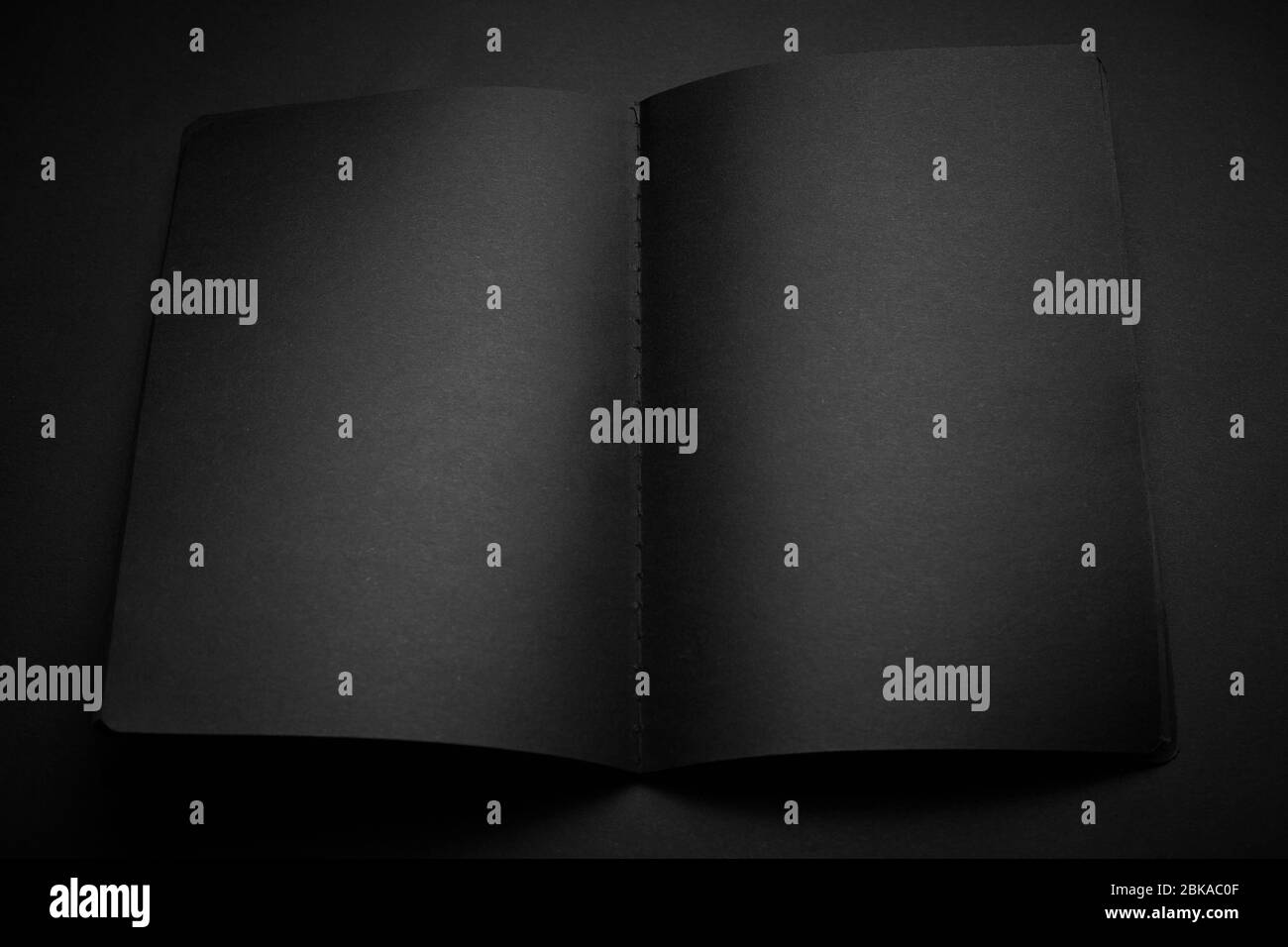 Blank black notebook on a black table, mockup photo. Blank black cover ...