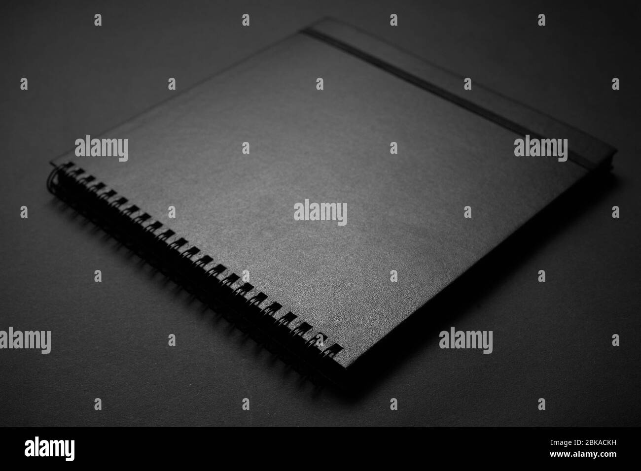 Blank black notebook on a black table, mockup photo. Blank black cover ...