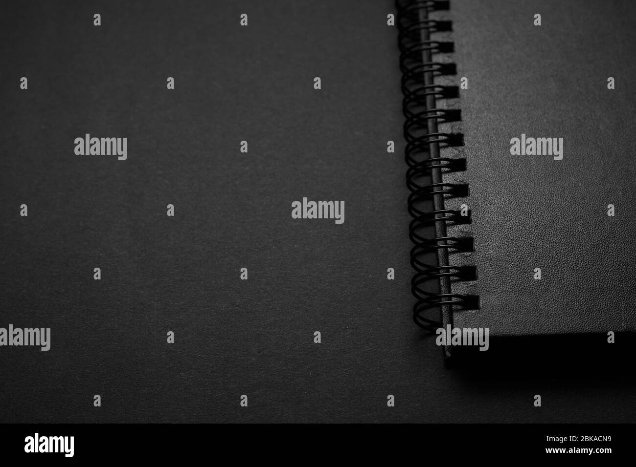 Blank black notebook on a black table, mockup photo. Blank black cover ...