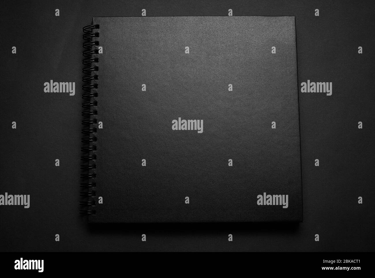 Blank black notebook on a black table, mockup photo. Blank black cover ...