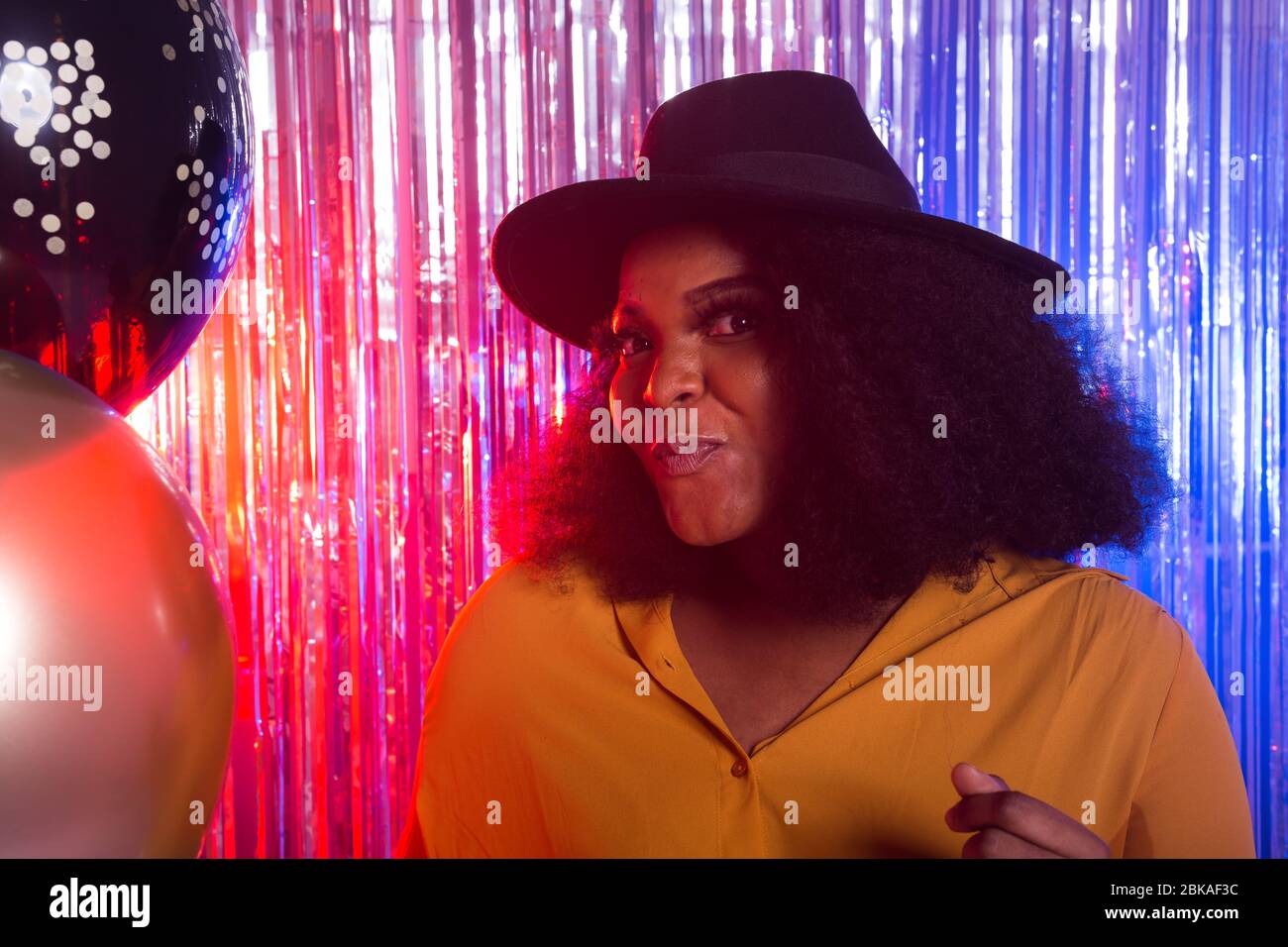 Young black woman looks happy while spend time in night club. Birthday ...