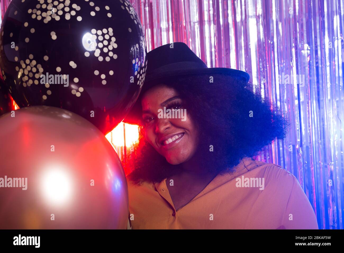 Young black woman looks happy while spend time in night club. Birthday ...