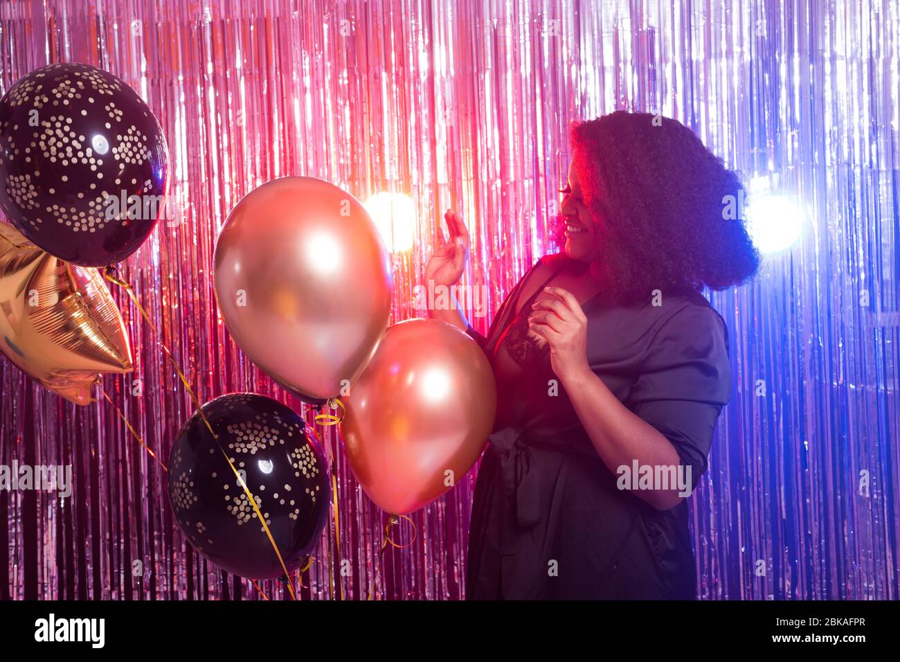 Young black woman looks happy while spend time in night club. Birthday ...
