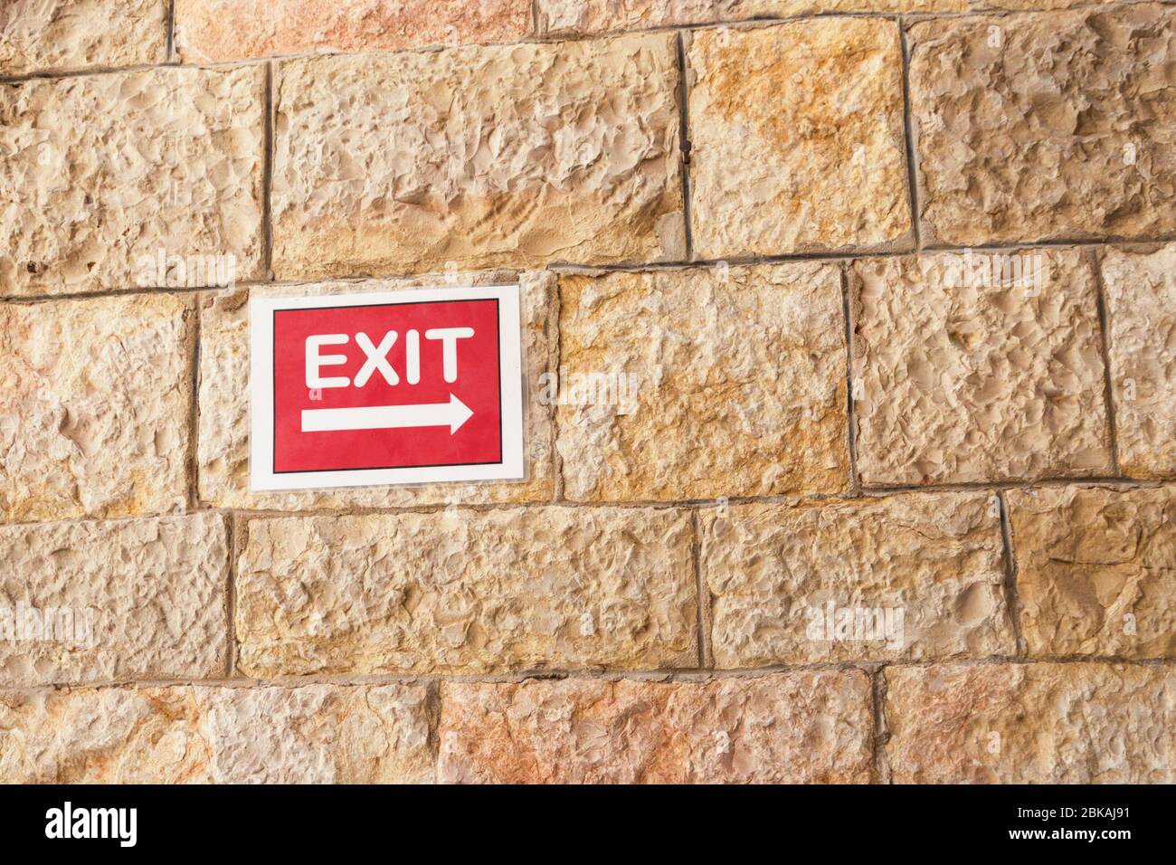 Red exit sign on sandstone textured wall background Stock Photo - Alamy