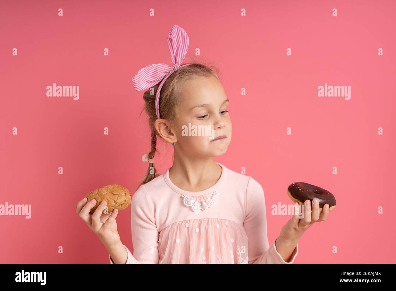 Little blonde model in dress, with headband and pigtail. Holding bun ...