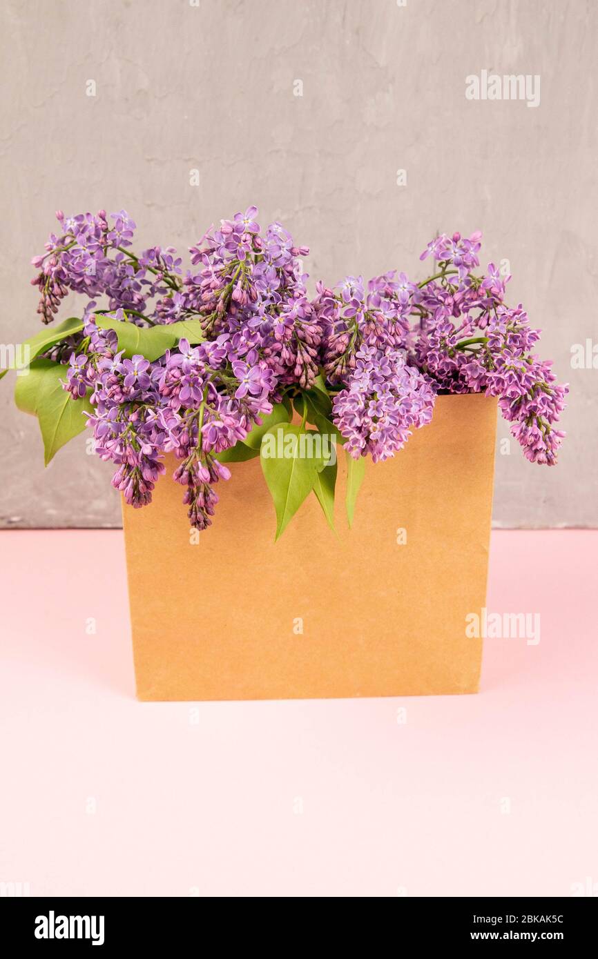 Paper craft package with lilac flowers over pink background. Creative ...