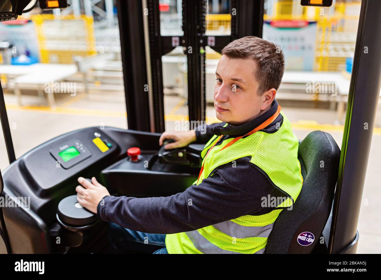 Storehouse employee in uniform working on forklift in modern automatic ...