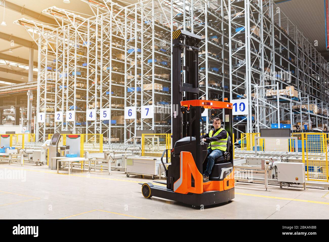 Storehouse employee in uniform working on forklift in modern automatic ...