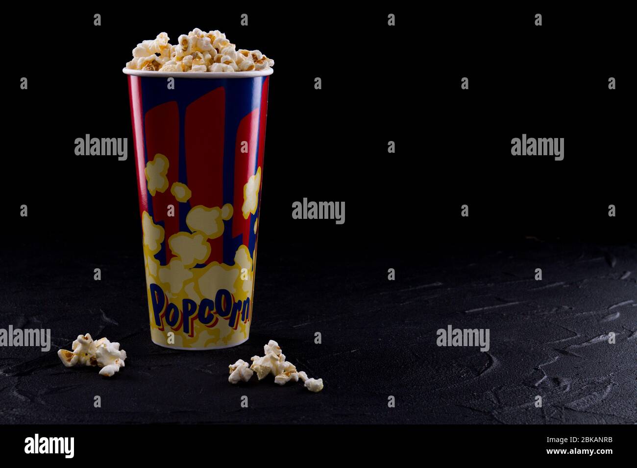 Full popcorn in classic popcorn box on very dark background Stock Photo ...