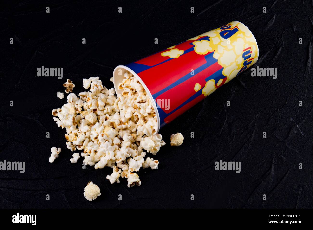 Tasty popcorn spilled from a overturned box dark background Stock Photo ...