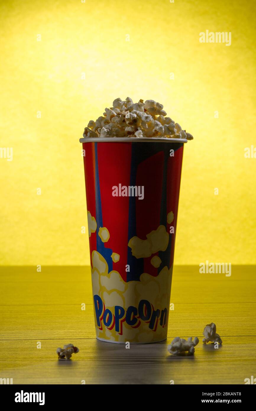Full popcorn bucket on a yellow background Stock Photo - Alamy