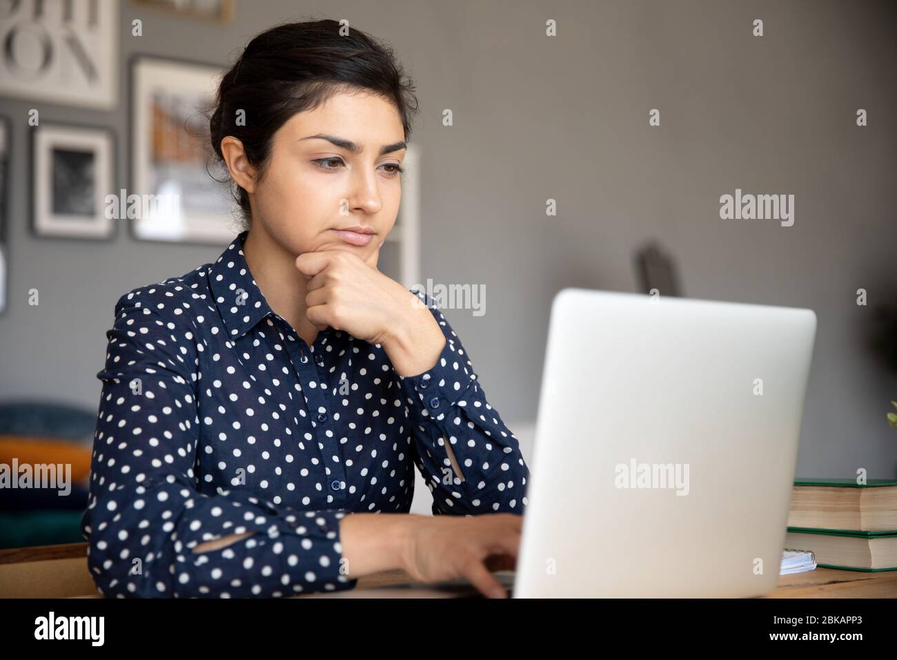 Thoughtful young indian woman looking at computer screen Stock Photo ...