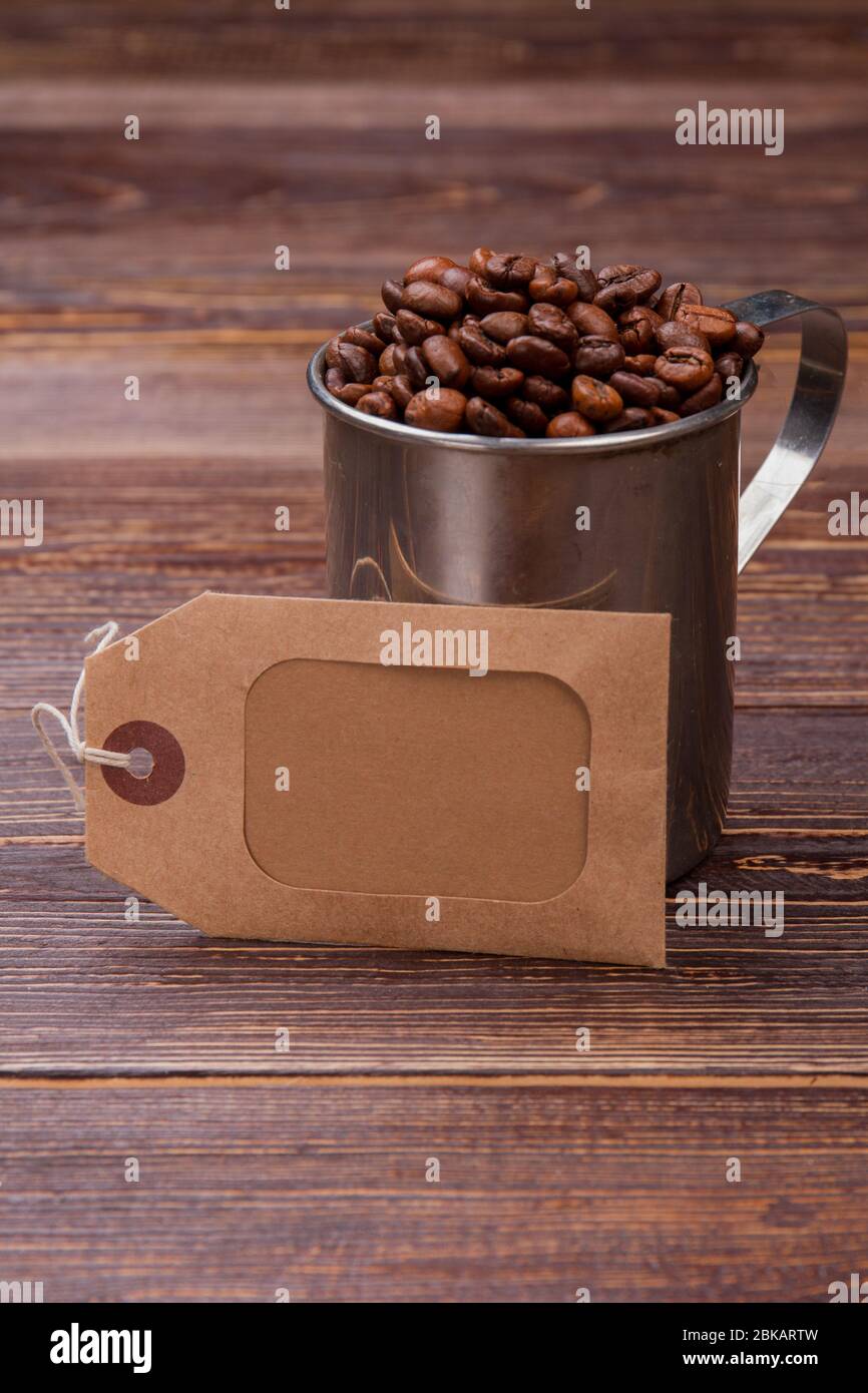 Steel mug with coffee beans and tag for copy space Stock Photo - Alamy