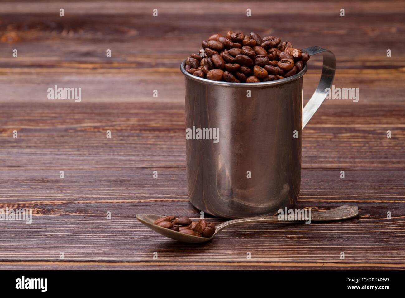 Steel mug and teaspoon filled with coffee beans Stock Photo - Alamy