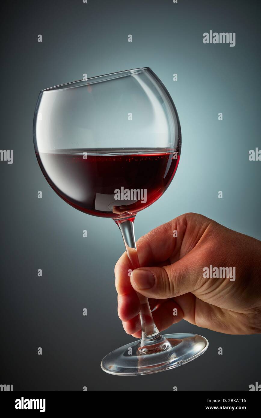 glass on red wine in human hand Stock Photo - Alamy