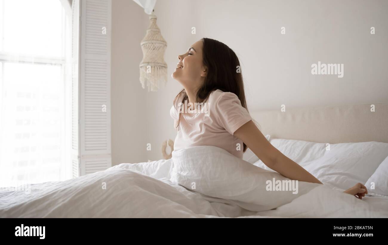Happy young girl wake up in cozy white bed Stock Photo - Alamy