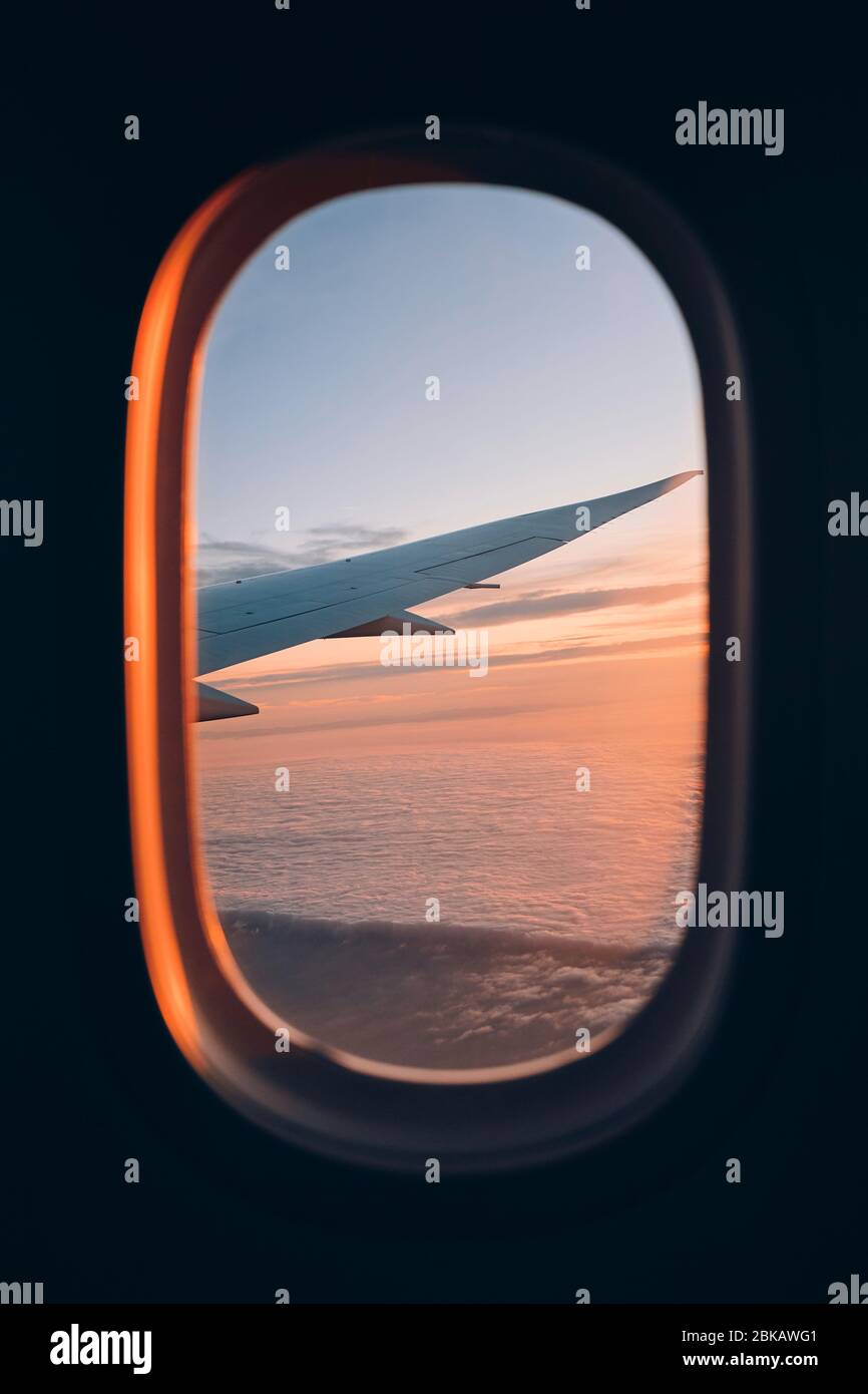 View from window of airplane during flight above clouds at beautiful sunset. Selective focus on ...