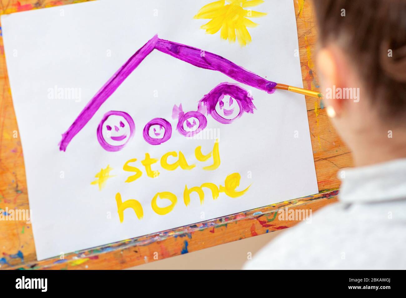 LIttle girl is drawing family under a roof with words Stay Home on the ...