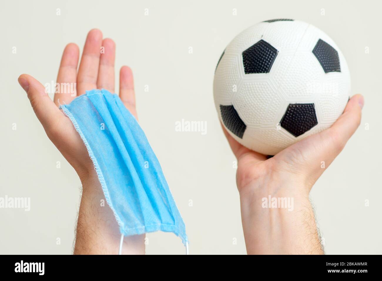 Soccer ball and medical mask in man hands up on white background Stock ...